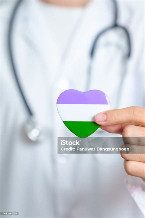퀴어 프라이드의 날과 Lgbt 프라이드의 달 개념 레즈비언 게이 양성애자 트랜스젠더 젠더퀴어 범성애자 커뮤니티를 위한 청진기로 보라색 흰색 녹색 하트 모양을 들고 있는 의사