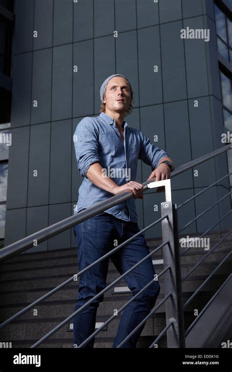 Portrait Of Young Man Standing On Stairs Looking At Distance Stock