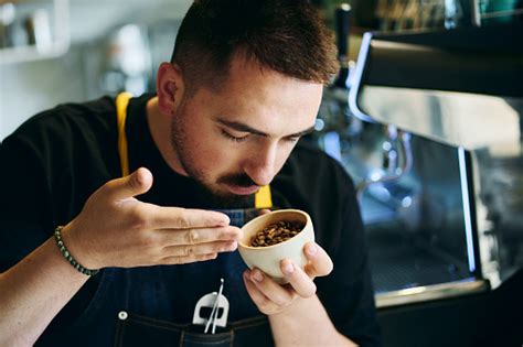 바리스타는 상업용 커피 머신에서 커피를 만들기 전에 커피 원두로 컵 냄새를 맡습니다 바리스타에 대한 스톡 사진 및 기타 이미지