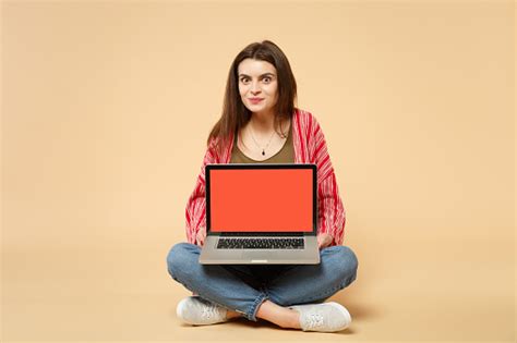 앉아 캐주얼 옷에 즐거운 젊은 여자 파스텔 베이 지 배경에 고립 된 빈 빈 화면으로 노트북 Pc 컴퓨터를 들고 사람들은 진심으로 감정 라이프 스타일 개념입니다 복사 공간을