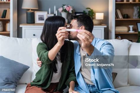 기대 원하는 임신 젊고 행복한 커플 남자와 여자가 소파에 앉아서 임신 테스트기를 보고 있습니다 새로운 생명 개념 긍정적 인 임신