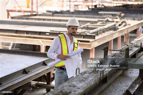 안전모를 쓴 젊은 엔지니어가 건설 현장에서 작업을 검사하고 시멘트를 붓고 있는 공장에서 30 34세에 대한 스톡 사진 및 기타 이미지 30 34세 건설 기계류 건설