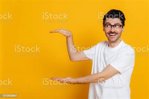 흥분 깜짝 놀랄 행복한 백인 흰색 티셔츠와 안경 외모와 프리젠 테이션을위한 빈 공간에 손으로 보여주는 고립 된 오렌지 배경에 서