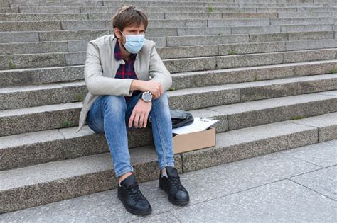 직장을 잃을 절망에 개인 소지품 상자와 야외 계단에 앉아 의료 마스크에 불행한 슬픈 사업가 실업률은 전염병으로 인해 상승하고 있습니다 해고 된 비즈니스 문제 개념에 대한