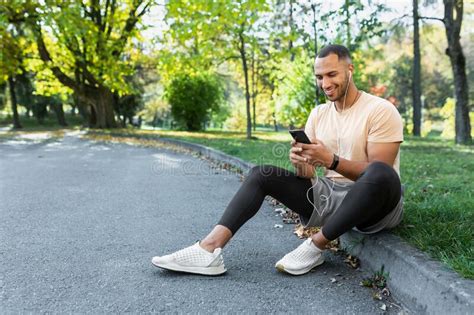 Happy And Satisfied Man After Jogging And Fitness Class Sitting And Using Smartphone African Happy And Satisfied Man After Jogging And Fitness Class Sitting And Using Smartphone African