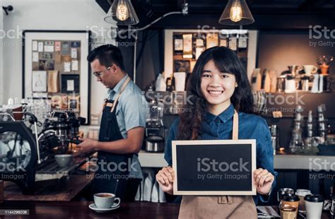 아시아 여성 바리 스타 의류 장 앞치마 지주 빈 칠판 커피 메뉴 스마일 얼굴 카페 서비스 컨셉 비즈니스 소유자를 가진 동료와