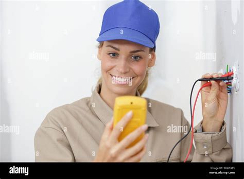 Happy Female Electrician Testing A Wall Socket Stock Photo Alamy
