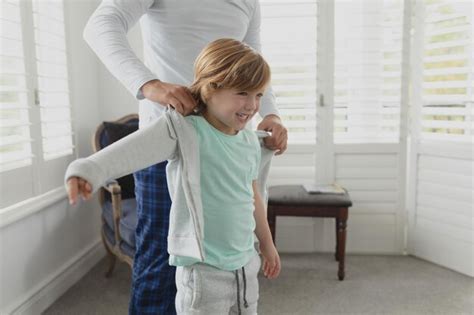 Padre Ayudando A Su Hijo A Vestirse Foto Premium