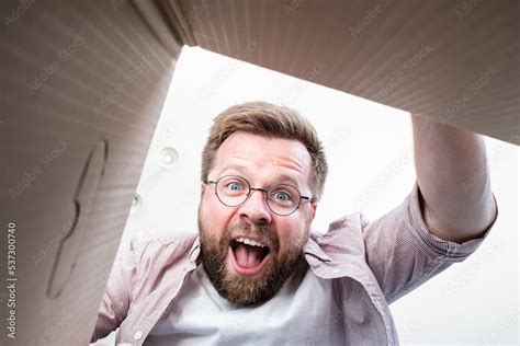 Man With Glasses Unpacked The Delivered Box With A Parcel Looks At The Contents Shouts With