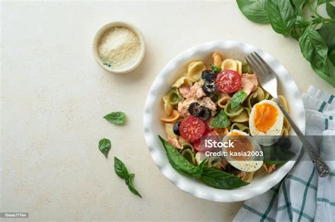 이탈리안 파스타 샐러드 참치 토마토 체리 올리브 바질 파마산 치즈를 곁들인 오레키엣 파스타는 회색 돌이나 콘크리트 배경에 접시에