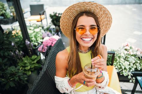 Sunlit Cafe Outing With A Smiling Woman Wearing A Sunhat Enjoying A