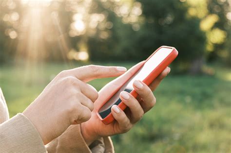 스마트 폰을 이용한 여성 손의 클로즈업 자연 배경 야외에서 일몰에 휴대 전화를 사용하는 여성 스마트 폰 화면을 만지는 인식 할