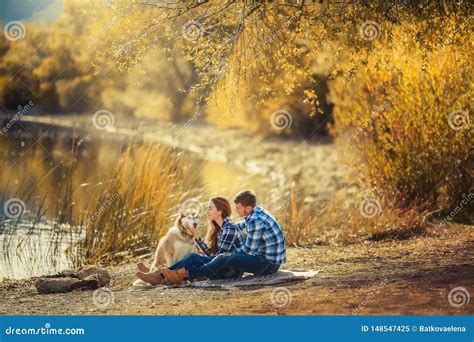 M Oda Para Siedzi Jeziorem Przy Zmierzchem Z Uskowatym Trakenu Psem Obraz Stock Obraz
