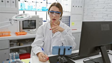 A Brunette Woman In Safety Glasses Conducting Research In A Well Equipped Laboratory Filmed By