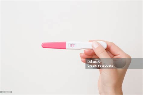 회색 바탕에 줄무늬 두 임신 테스트를 개최 하는 젊은 여자의 손 긍정적인 결과입니다 근접 촬영입니다 포인트 보기 샷입니다