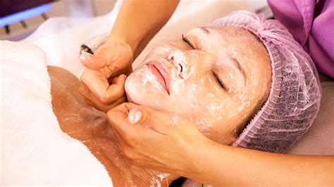 미용사는 여성 얼굴에 보습 마스크를 적용합니다 얼굴 관리를위한 미용 절차에 스파 살롱에있는 여성 미용 치료 치료를받는 백인 여성