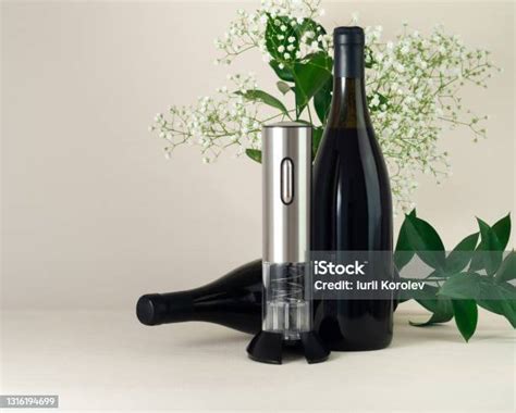 스탠드에 금속으로 만든 전기 코르크 나사 인근에는 와인 2병이 있습니다 배경에 장식꽃과 가지 라이트 백 0명에 대한 스톡 사진 및 기타 이미지 Istock