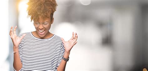 아름 다운 젊은 아프리카계 미국인 여자에 안경을 절연 배경 화 축 하 하 고 무기와 성공을 위해 미친 제기 흥분 비명 눈을 폐쇄 우승자 개념 매우 기쁜에 대한 스톡 사진 및