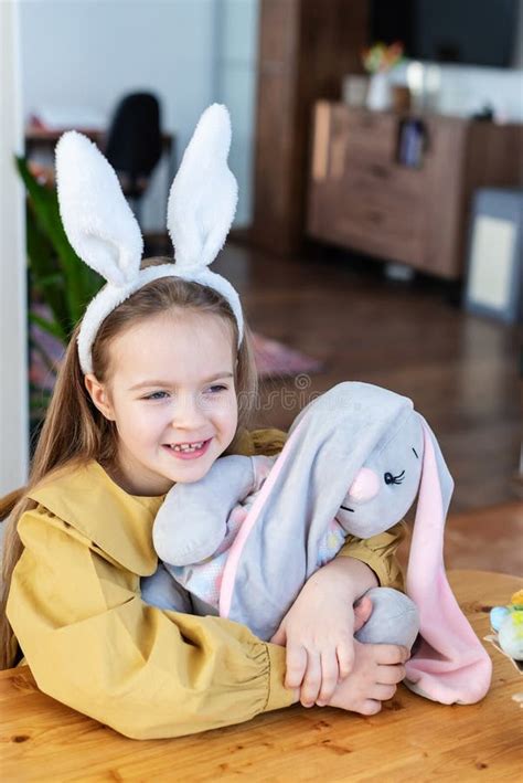 Smiling Caucasian Young Girl With Bunny Ears Holding Plush Rabbit Toy