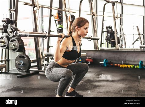 Cute Girl Has A Hard Athletic Workout In The Gym Doing Squats With