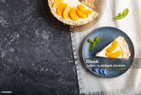 검은 색 콘크리트 배경에 린넨 냅킨에 파란색 꽃이 있는 파란색 세라믹 접시에 복숭아 치즈 케이크 조각 상단 보기 복사 공간 검은