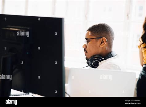 Side View Of Computer Programmer With Headphones Sitting Against Window