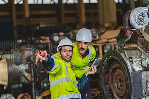산업 제조 공장에서 일하는 안전 헬멧 하드 모자를 가진 직업적인 기술공 엔지니어 기계장치 생산 기술 또는 건축 운영의 장비를