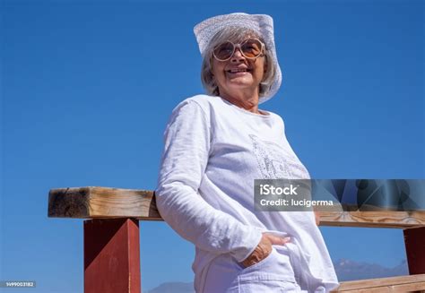 화창한 날에 야외에 서 있는 모자를 쓴 하얀 옷을 입은 노파 자유와 여름 휴가를 즐기는 노인 관광에 대한 스톡 사진 및 기타 이미지 Istock