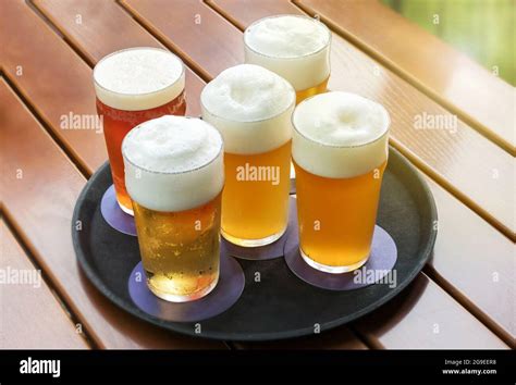 Five Cold Beers With Frothy Heads In Glasses On A Tray On A Slatted