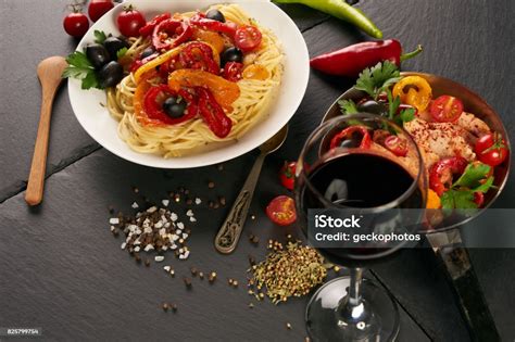 알프레도 파스타올리브 치킨 크림 소스 스파게티와 치킨 필렛 야채 토마토 파프리카와 마늘 녹색 바 질 올리브와 어두운 슬레이트 테이블에 조미료 향신료 0명에 대한 스톡 사진