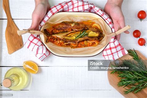 손은 갓 요리 한 생선을 잡습니다 야채 향기로운 허브 흰색 나무 테이블에 올리브 오일 복사 공간 플랫 레이가 있는 상단 뷰입니다 음식 배경 가정 생활에 대한 스톡 사진 및