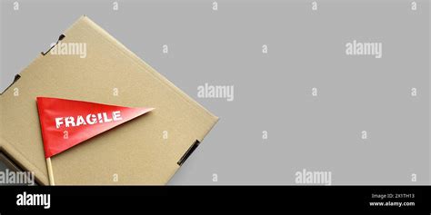 One Cardboard Packaging Box On Monochrome Background Tiny Red Paper Flag With The Warning