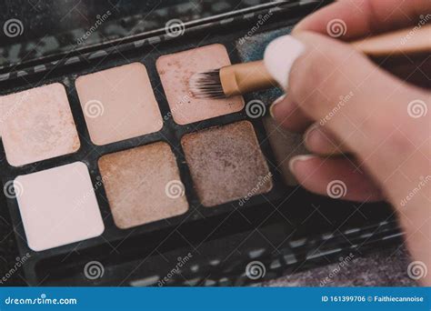 Make Up Brush Tapping On Eyeshadow With Natural Nude Tone Among Other Colors In A Palette Stock