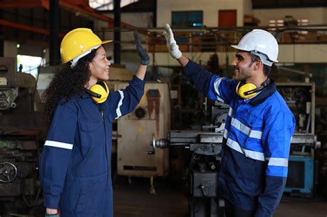 행복한 미소 짓는 팀워크 기술자 엔지니어 또는 안전모를 쓴 보호 유니폼을 입은 노동자는 중공업 제조 공장에서 함께 성공적인 거래 약속을 축하합니다 16 17 살에 대한 스톡