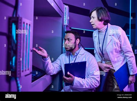 Hindu Male And Adult Female Scientists Engage With Computer In Neon Lit