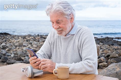 Smiling Beautiful Senior Man Holding Mobile Phone Reading A Message In