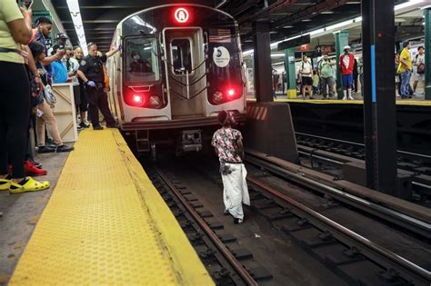 Man paces on NYC subway tracks, holds up trains