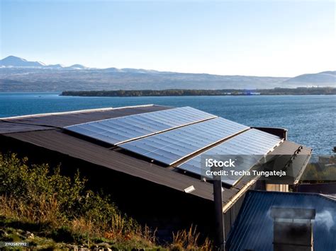 아름 다운 호수 전망 배경 근처의 작은 산업 공장 옥상에 태양 전지판 광전지 태양 에너지 개념 전기를 생산하기 위한 청정 에너지 방사선의 재생 가능한 원천 0명에 대한 스톡