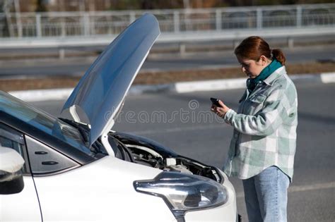 Caucasian Woman Looks Under The Hood Of A Car And Searches For Answers