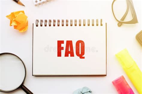 A Notebook Displaying The Word Faq Sits Next To A Magnifying Glass Symbolizing The Act Of