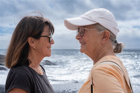 흐린 날 바다 앞에서 휴가를 보내는 노백인 커플의 여성 관광객 야외에서 자유와 건강한 생활 방식을 즐기는 두 명의 은퇴 한 여성의 측면 모습 2명에 대한 스톡 사진 및 기타