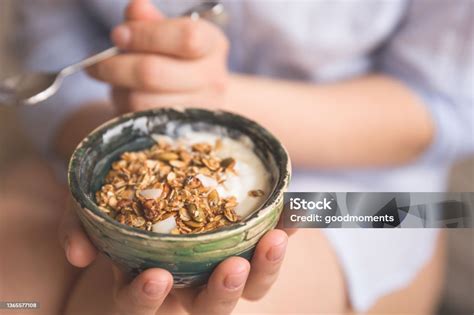Muesli 그릇으로 젊은 여자 그릇에 아침 시리얼에 견과류 호박 씨앗 귀리와 요구르트를 먹는 여자 여자 잡고 만든 놀라 건강 한 간식 또는 아침에 아침 식사입니다