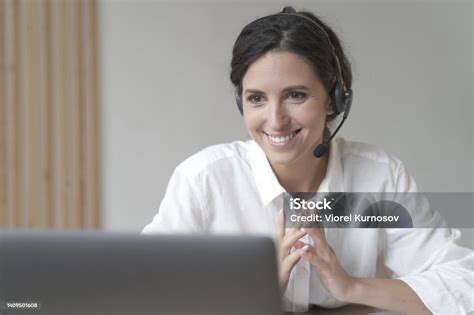 집에서 노트북으로 작업하는 동안 책상에 앉아있는 무선 헤드폰을 입은 이탈리아 사업가 웃는 여성 30 34세에 대한 스톡 사진 및