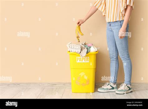 Woman Putting Garbage Into Full Trash Bin With PAPER Sign Near Beige Wall Recycling Concept