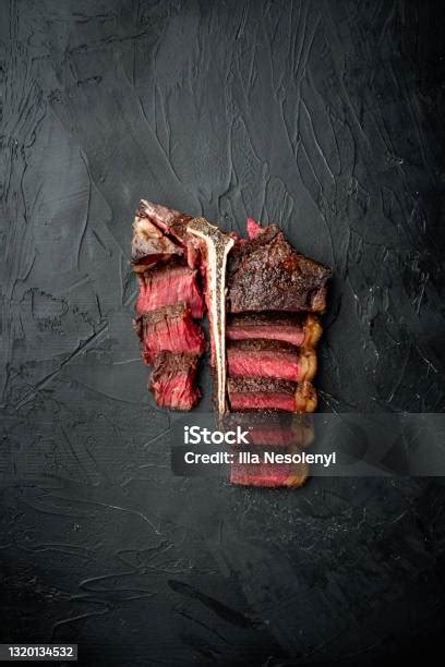 슬라이스 중간 희귀 구운 쇠고기 스테이크 T 뼈 또는 포터 하우스 컷 검은 돌 배경에 상단 보기 플랫 레이 텍스트복사 공간