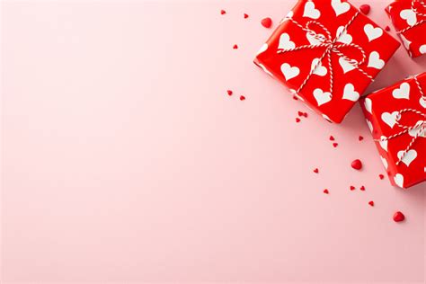 발렌타인 데이 개념입니다 하트 패턴이 있는 포장지에 담긴 선물 상자의 상위 뷰 사진과 복사 공간이 있는 격리된 파스텔 분홍색 배경에 뿌립니다 밸런타인데이에 대한 스톡 사진