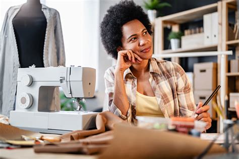 젊은 아프리카 계 미국인 기업가 여성은 작은 워크샵에서 일하면서 비용을 계산하고 재정적 어려움을 겪고 있습니다 그녀의 사업에
