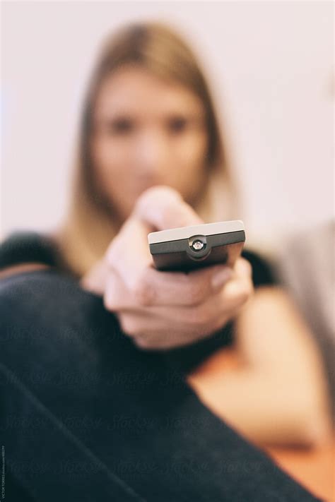 woman using a tv remote control by stocksy contributor victor torres