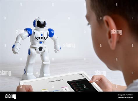 Boy Controls Robot Using Tablet On Desk Illustrating Education
