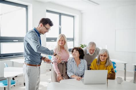 Teacher Explaining Senior Students How To Work With Laptop
